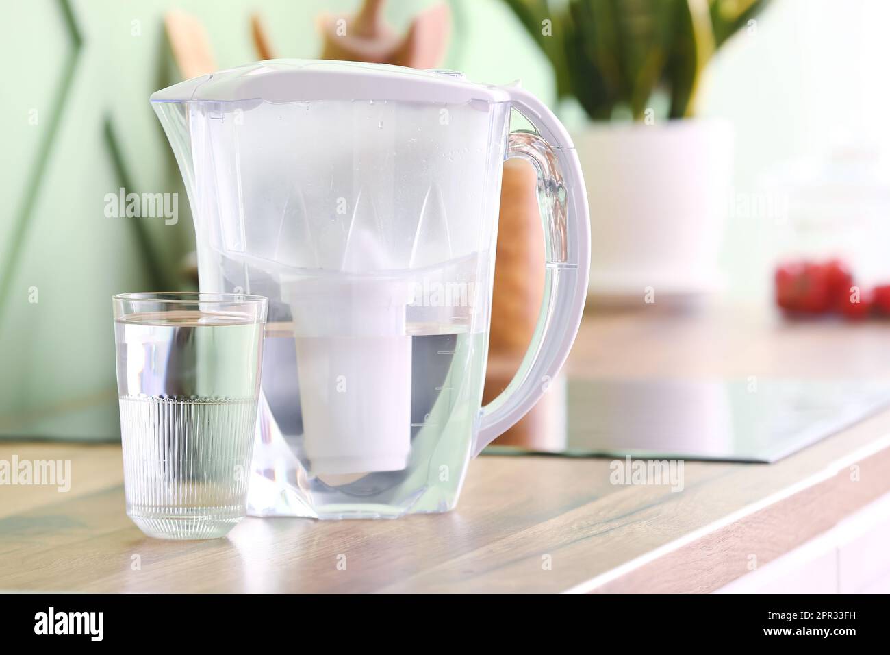 Modern filter jug and glass of water on kitchen counter Stock Photo - Alamy