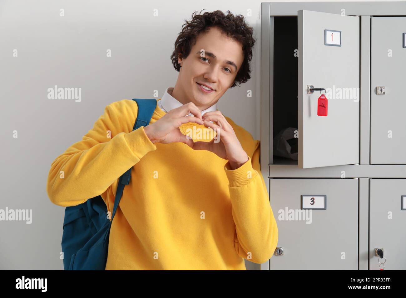 Teenage boy making heart with his hands near locker at school Stock ...