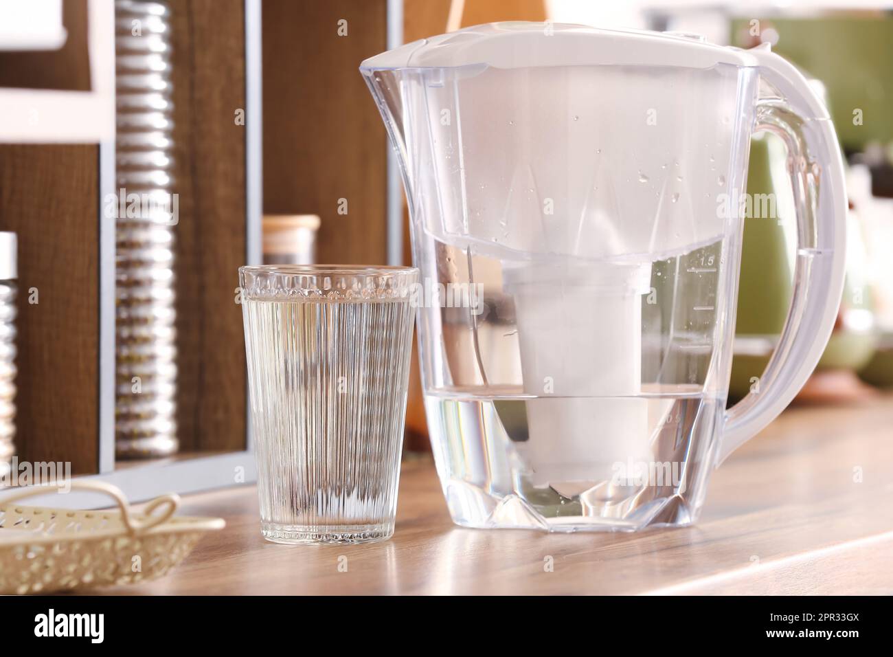 Modern filter jug and glass of water on kitchen counter Stock Photo - Alamy
