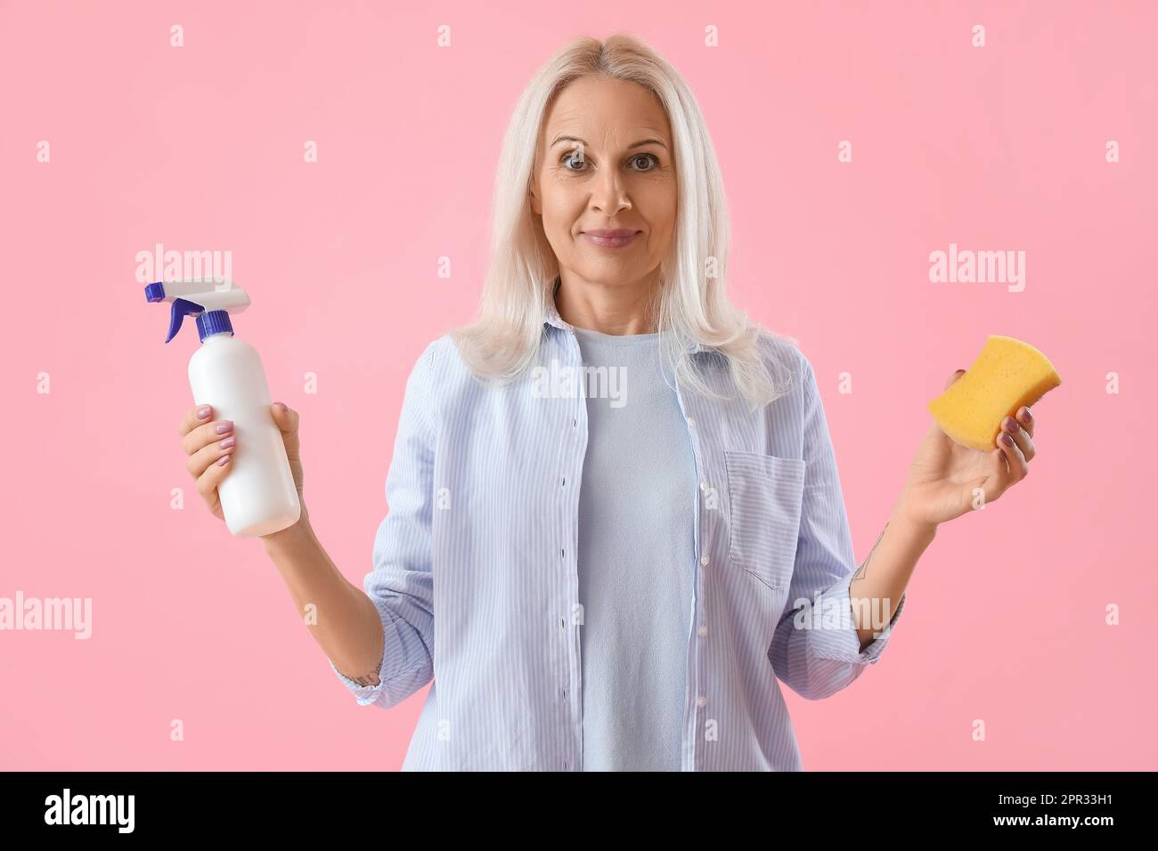 Mature woman with cleaning sponge and detergent on pink background ...