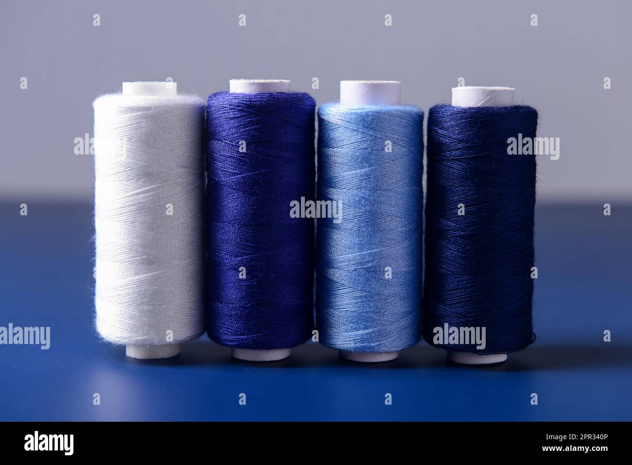 Set of different thread spools on blue background Stock Photo - Alamy