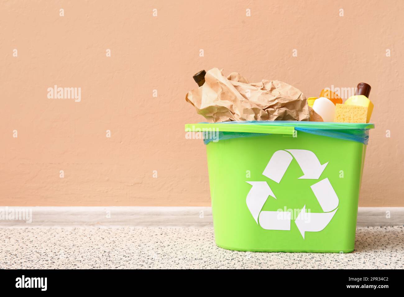 Trash bin with different garbage near beige wall Stock Photo - Alamy