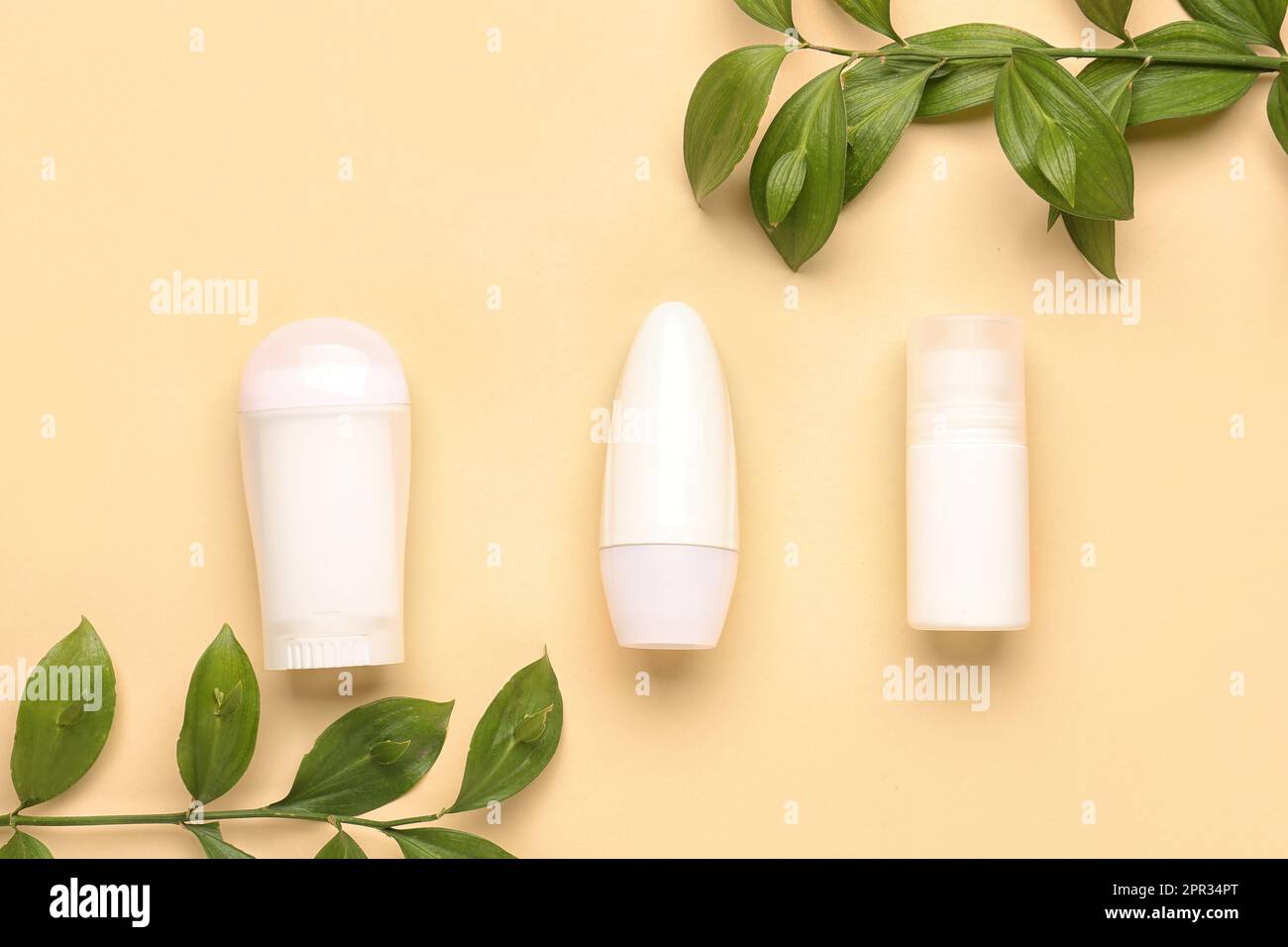 Different deodorant bottles and leaves on yellow background Stock Photo ...
