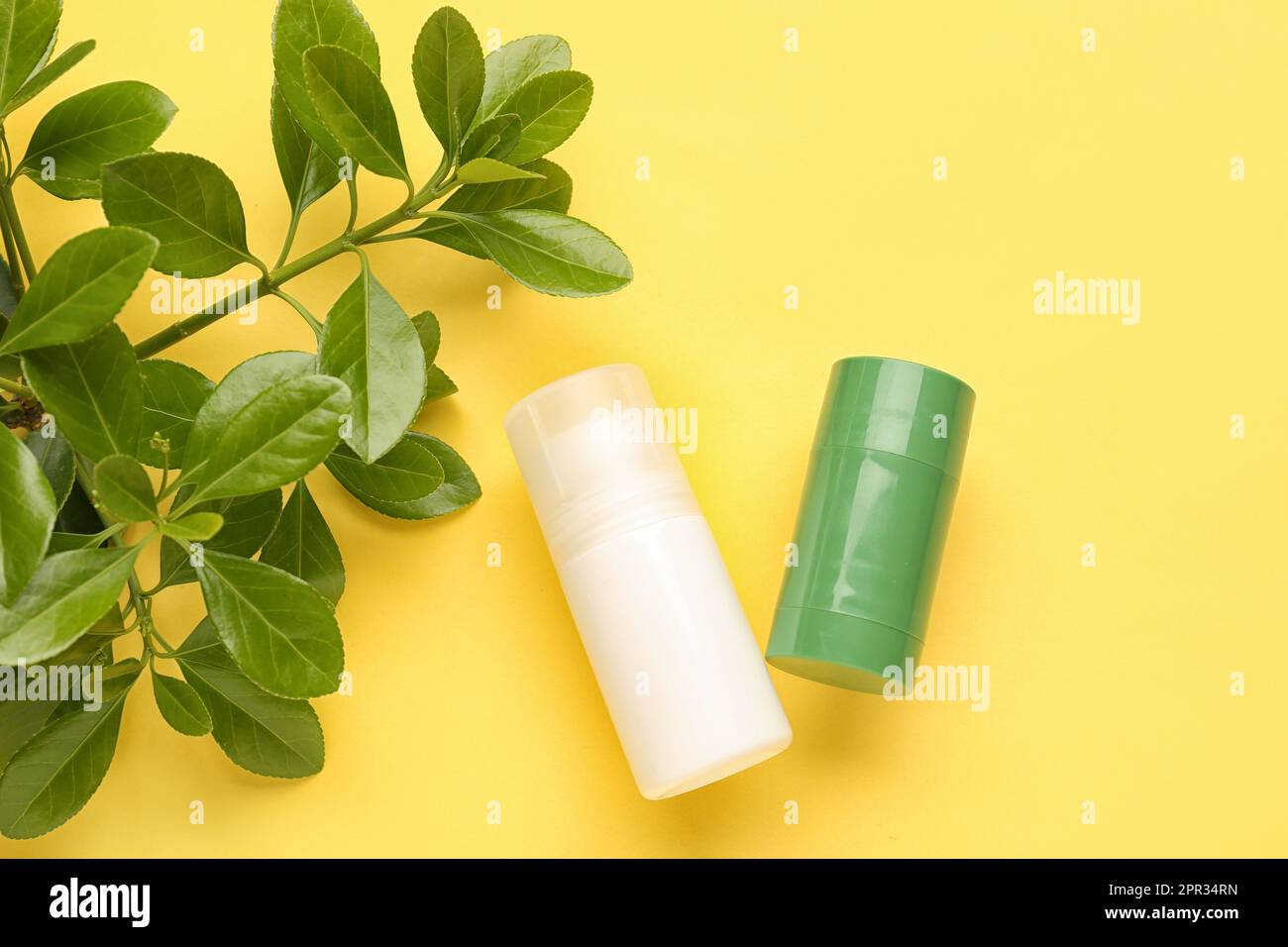 Different deodorant bottles and leaves on yellow background Stock Photo ...