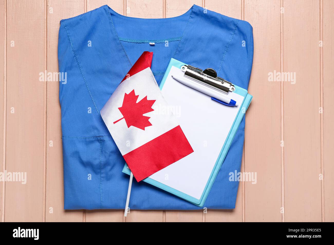 Canadian flag with doctor's uniform and clipboard on beige wooden ...