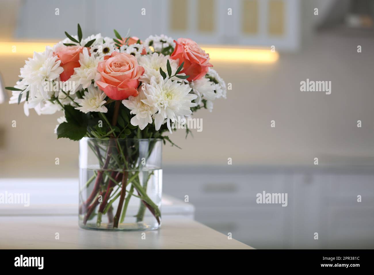 Vase with beautiful flowers on countertop in kitchen, space for text ...