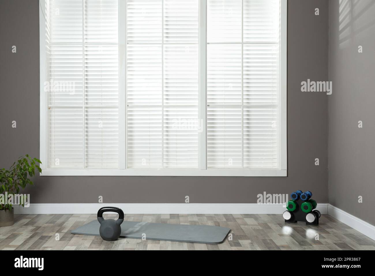Exercise mat with different dumbbells and kettlebell in spacious room ...