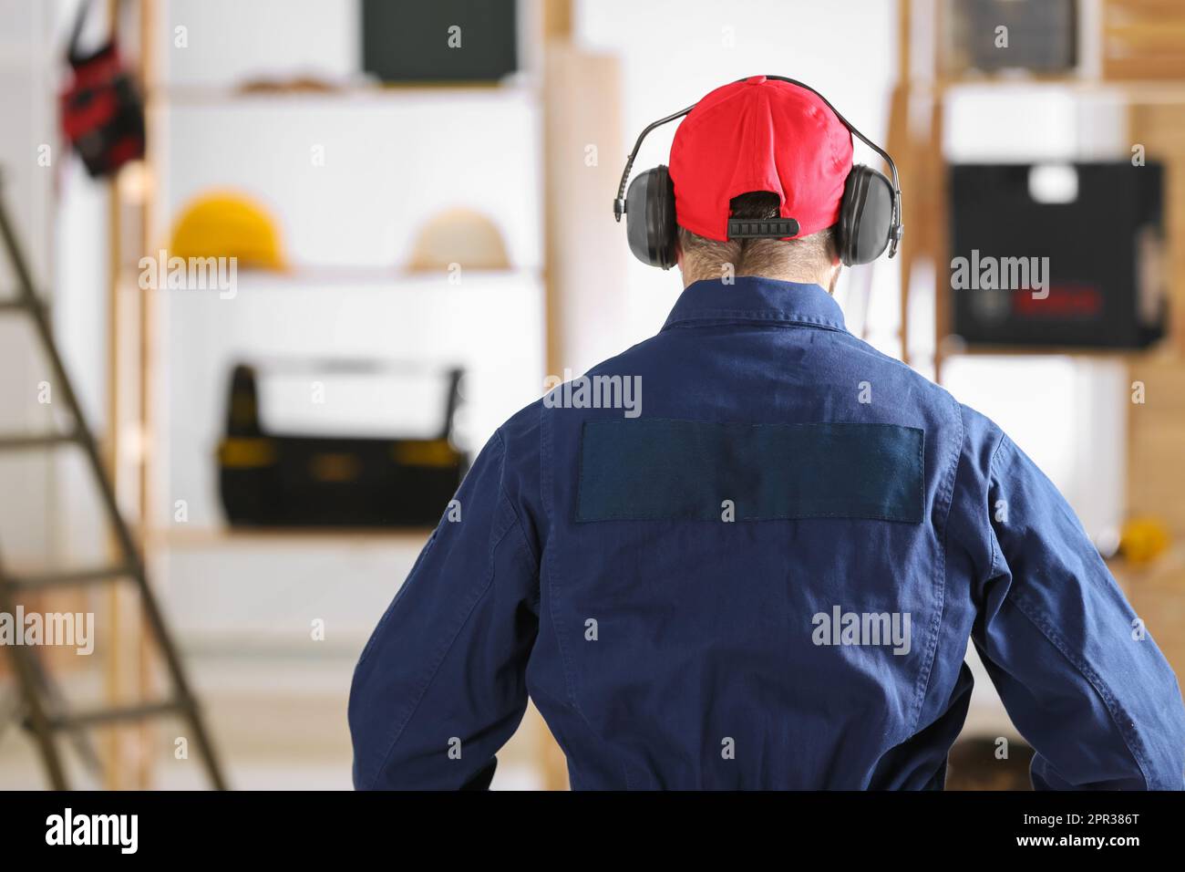 Worker wearing safety headphones indoors, back view. Hearing protection ...