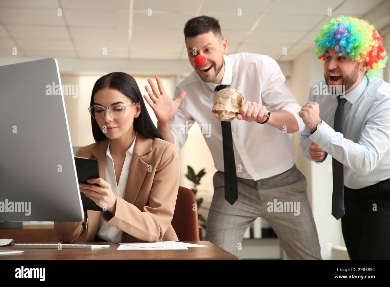 Men popping paper bag behind their colleague in office. Funny joke ...