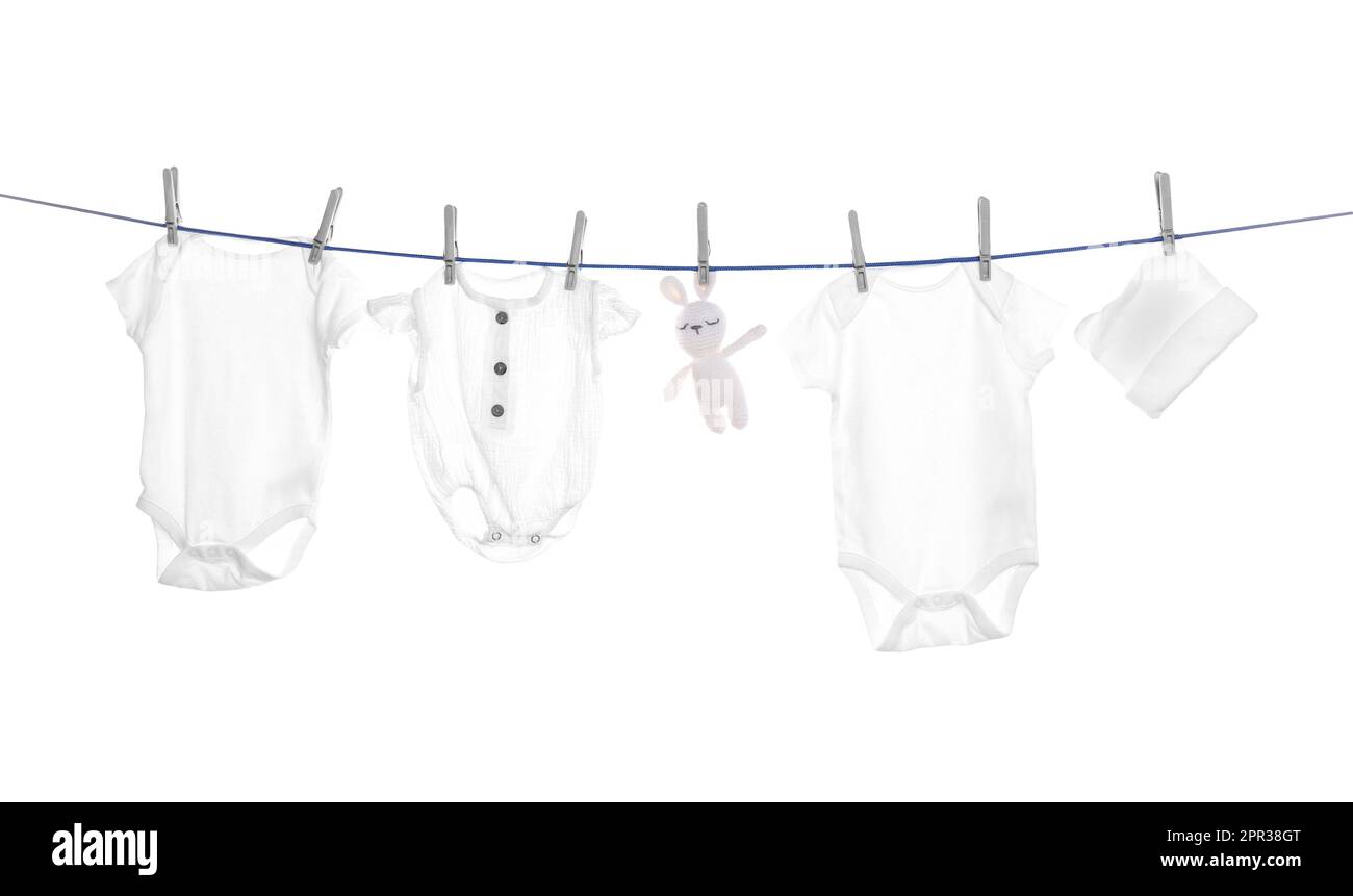 Different baby clothes and toy drying on laundry line against white ...