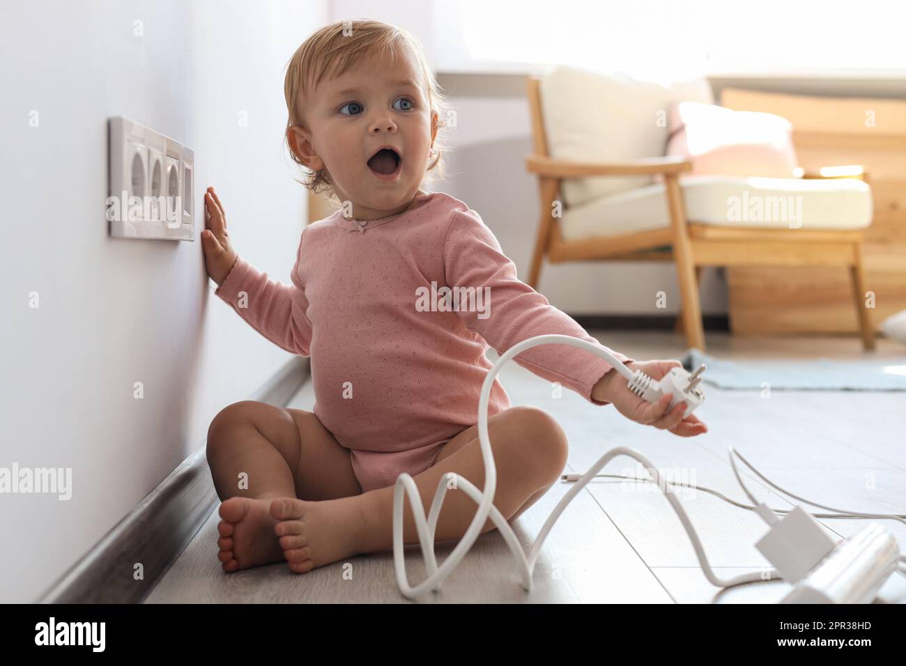 Cute baby playing with electrical socket and plug at home. Dangerous ...