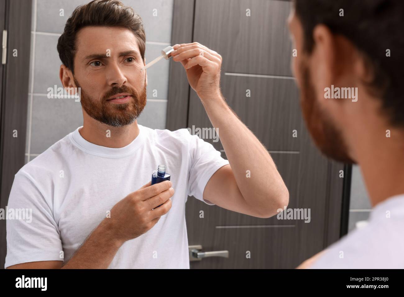 Handsome man applying oil on beard in bathroom Stock Photo - Alamy Handsome man applying oil on beard in bathroom Stock Photo - Alamy