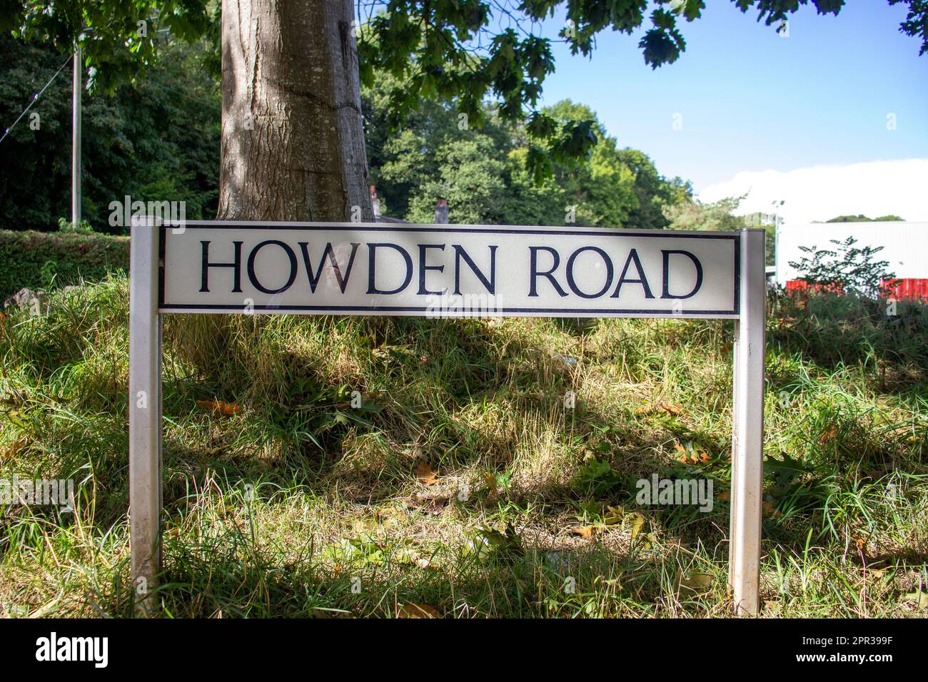 Howden Road street name sign on two posts with an old stone wall in the ...