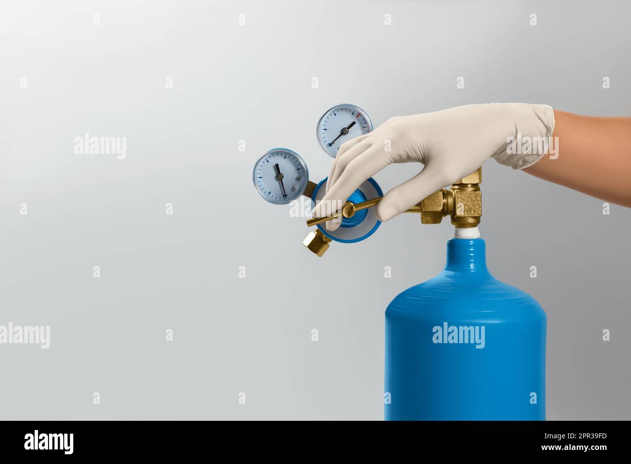 Medical worker checking oxygen tank on light grey background, closeup ...