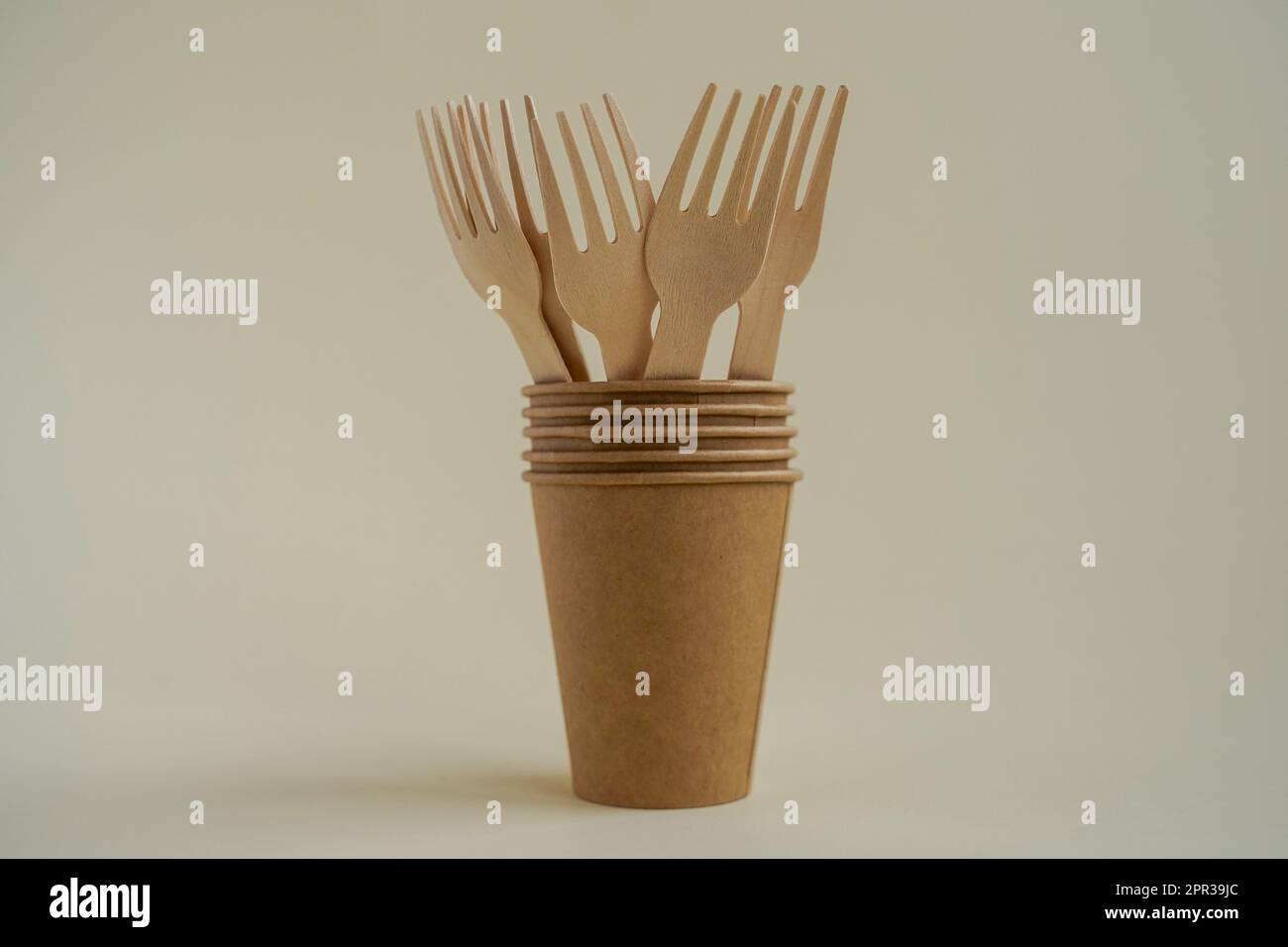 Paper cups with wooden forks on a white background. Recyclable garbage ...