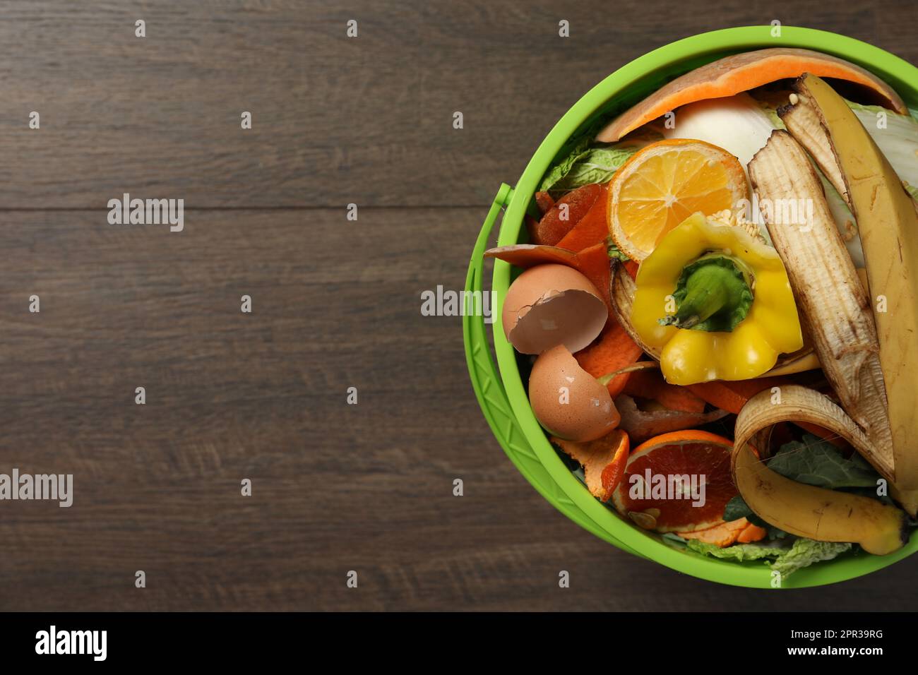 Natural garbage in trash bin on wooden background, top view with space ...