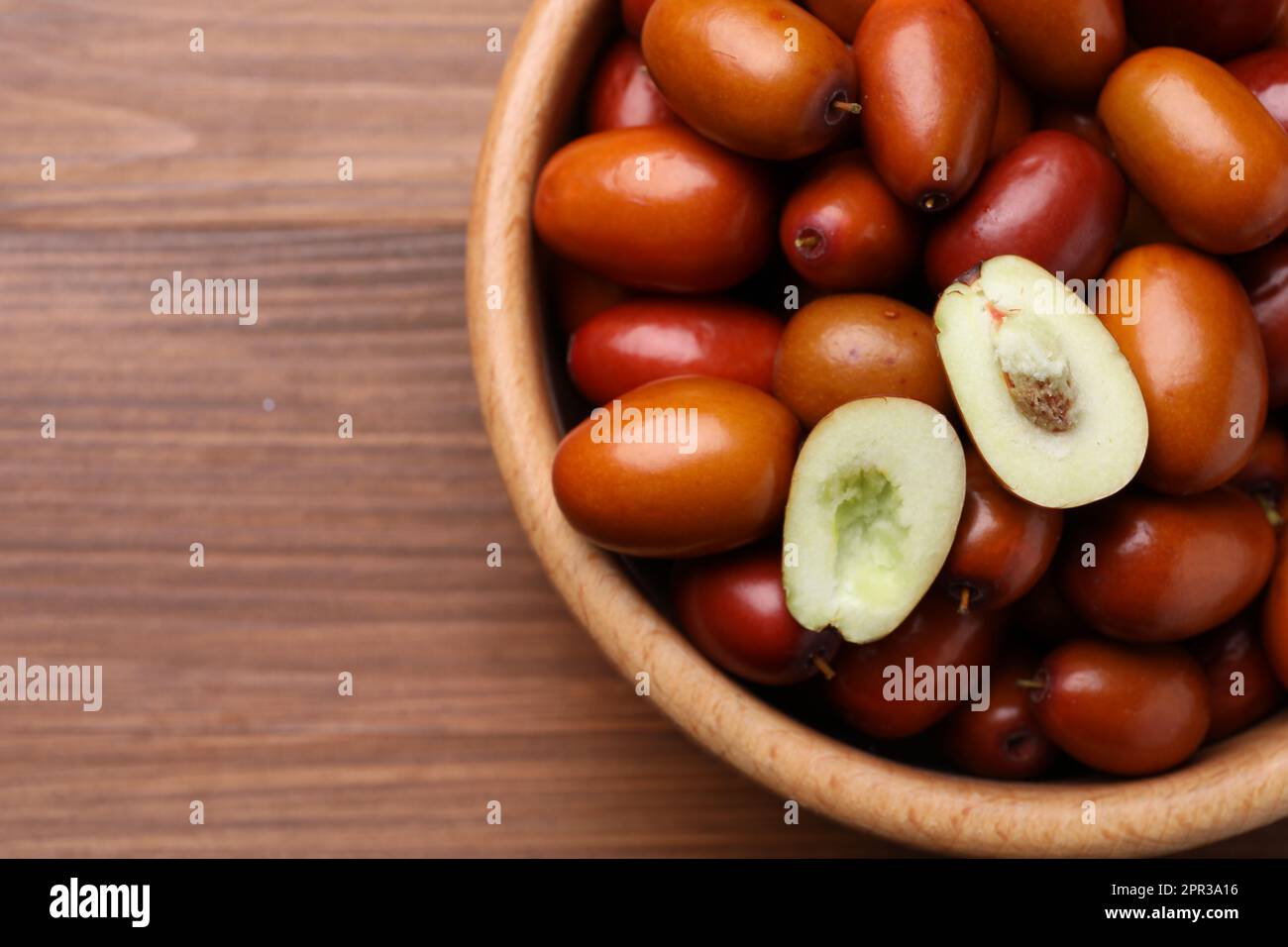 Fresh Ziziphus jujuba fruits in bowl on wooden table, top view. Space ...