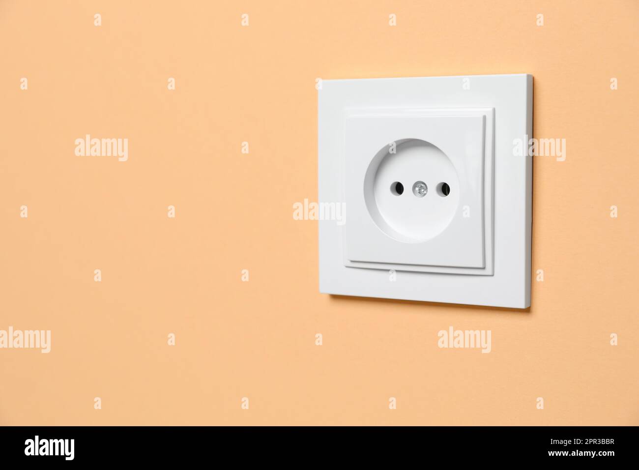 Power socket on pale orange wall, space for text. Electrical supply ...