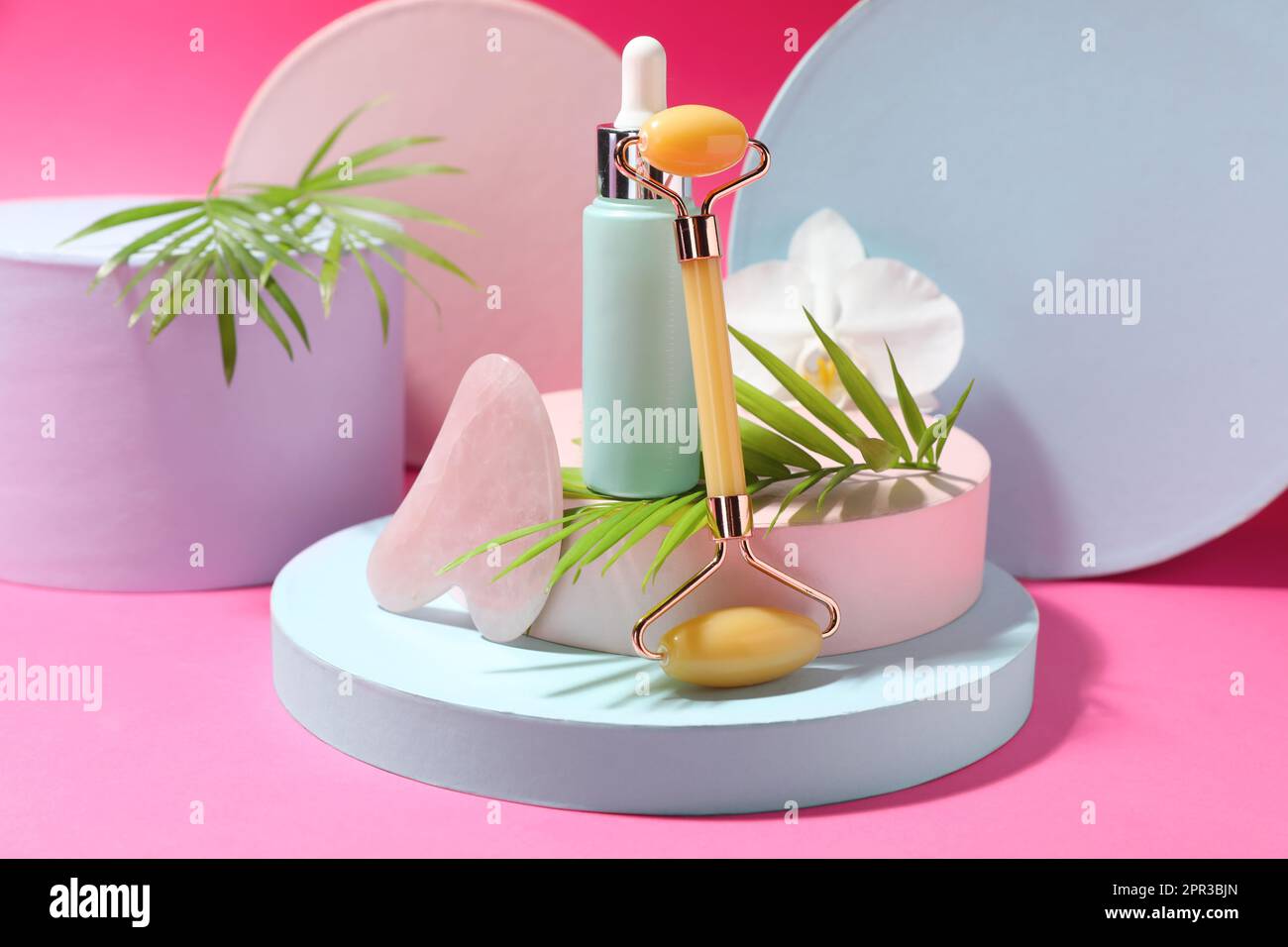 Beautiful composition with gua sha stone, face roller and bottle of ...