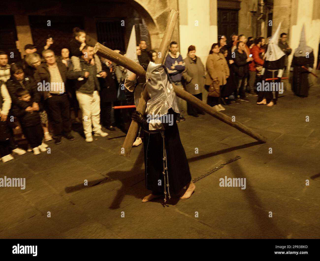 Penitents hide their identity with hoods, as they process with crosses ...