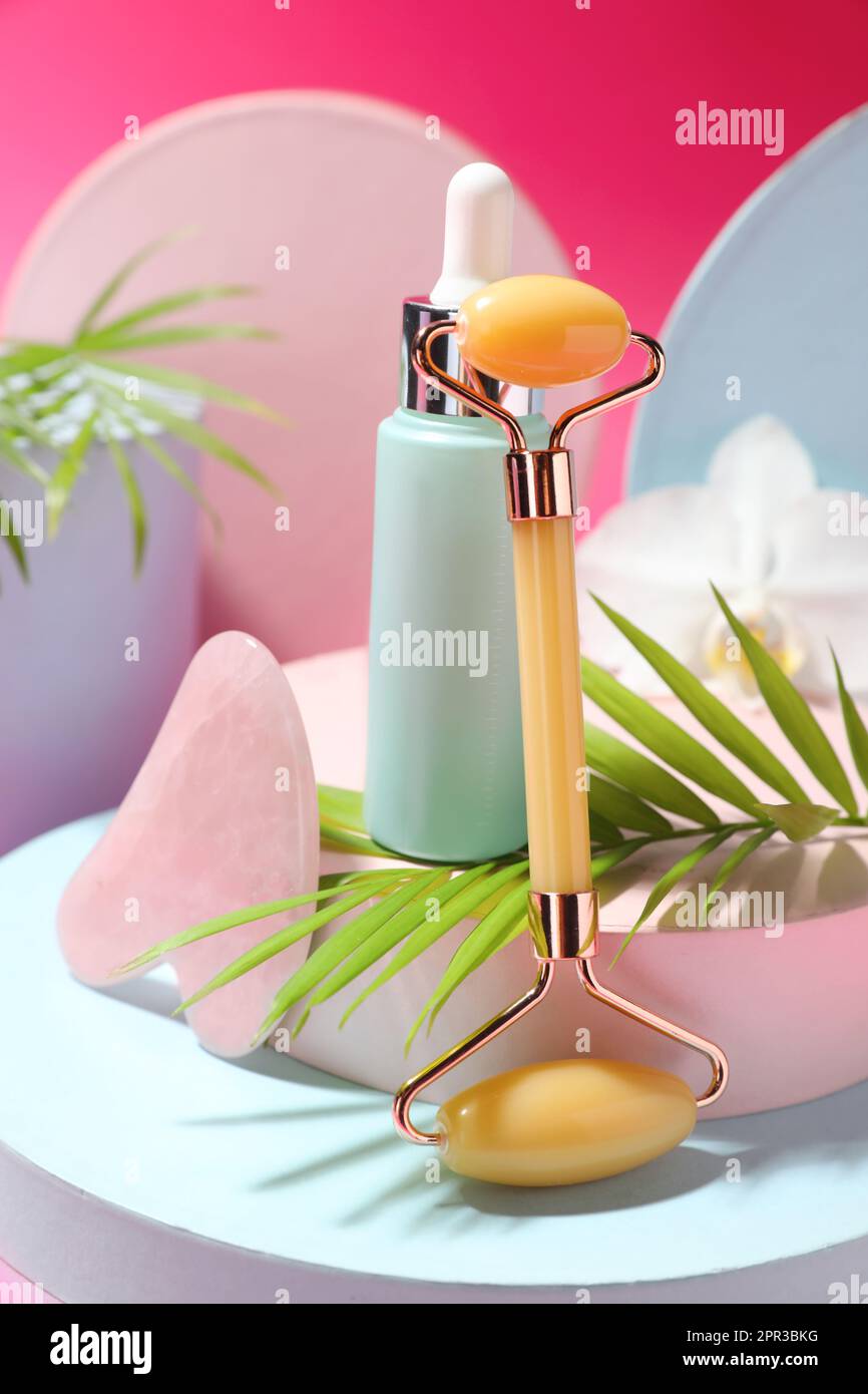 Beautiful composition with gua sha stone, face roller and bottle of ...