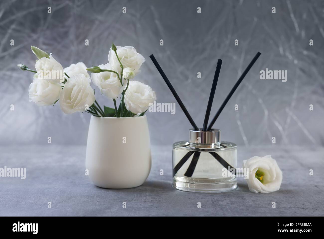 Reed diffuser and vase with eustoma flowers on gray marble table Stock ...