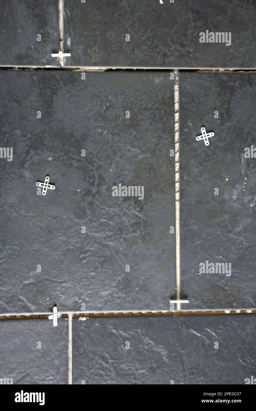 off centre black ceramic floor tiles and spacers being laid just before ...