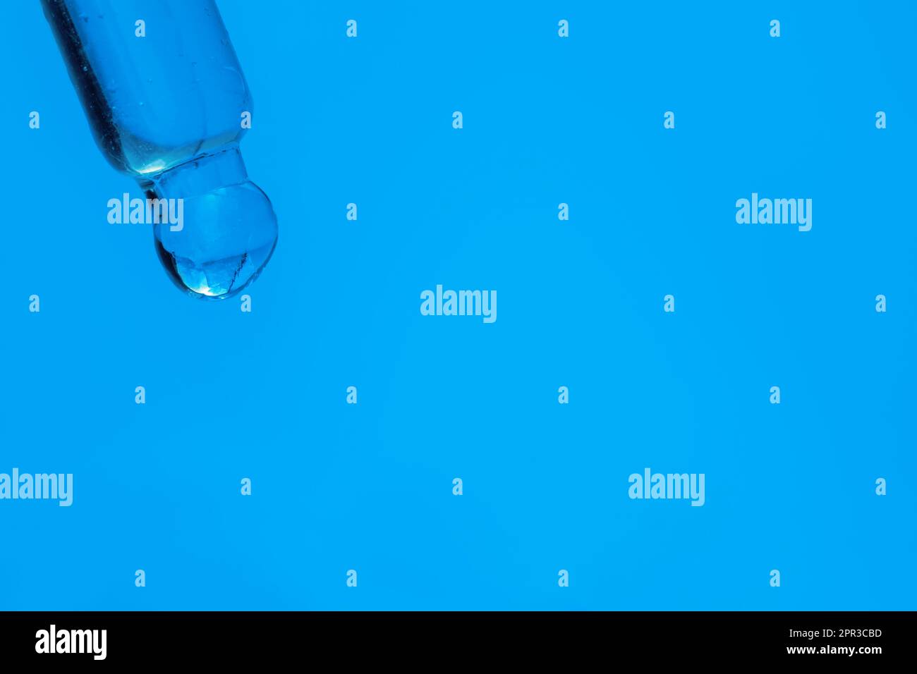 Dripping face serum from pipette on blue background, closeup. Space for ...