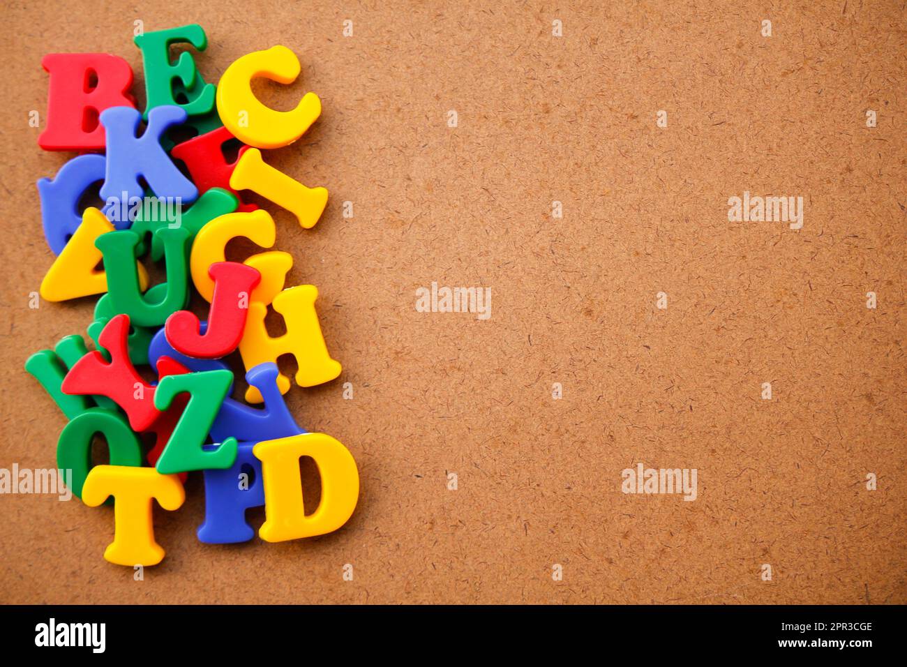 Colorful plastic alphabet letters scrambled on a wooden background ...