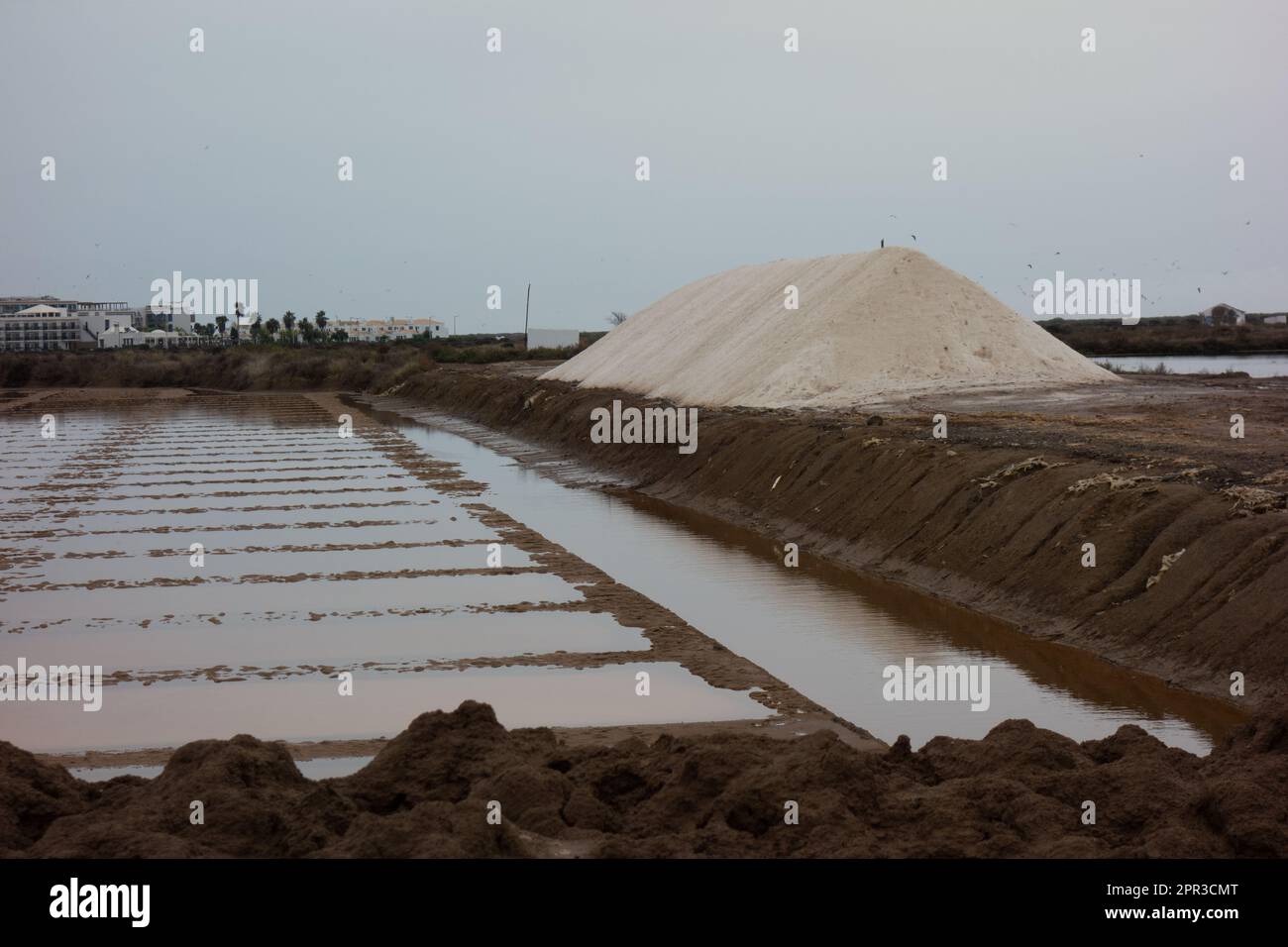 piles of salt at the Tavira salt pans in Southern Portugal on a grey ...