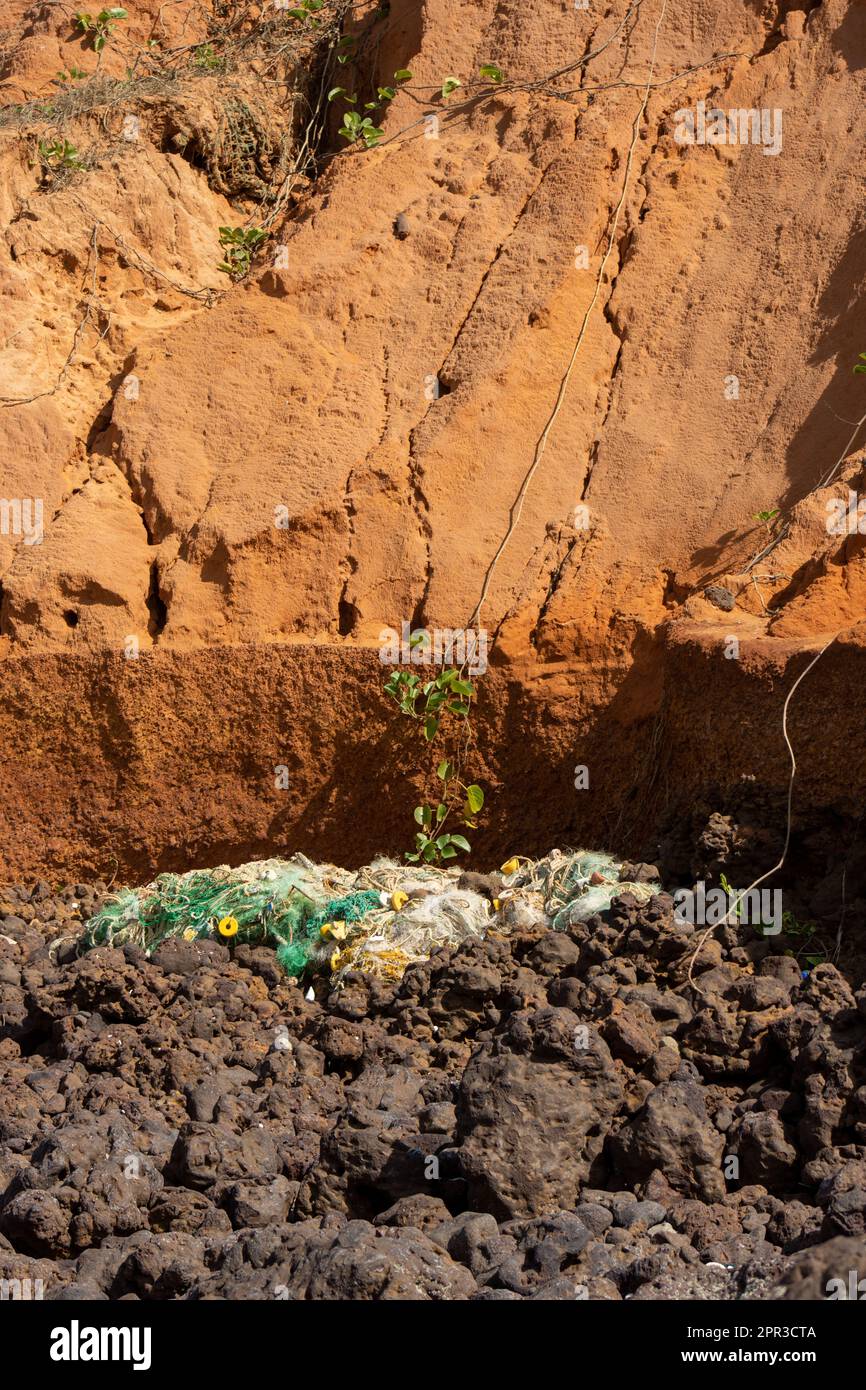 plastic rope, floats and nets washed up on a tropical beach with orange ...