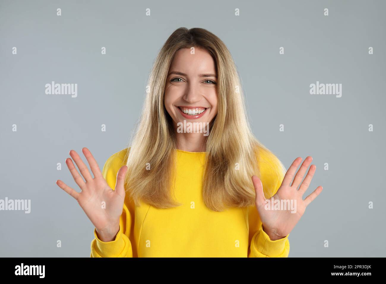 Woman showing number ten with her hands on light grey background Stock ...