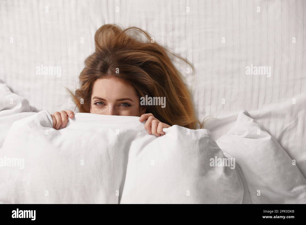 Woman hiding under warm white blanket in bed, above view Stock Photo ...