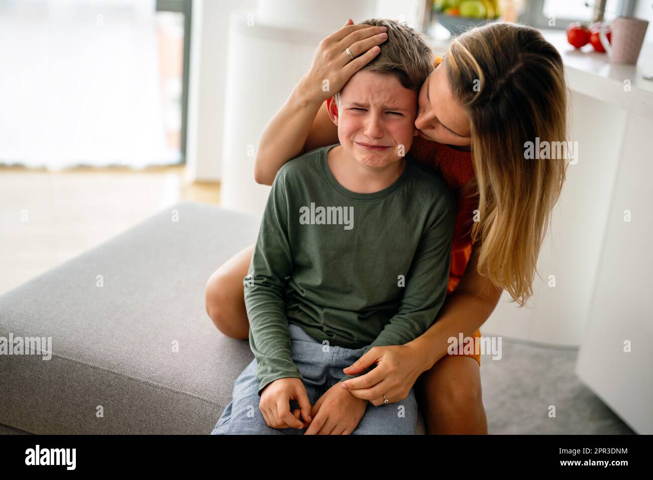 Portrait of mother consoling her crying sad injured son. Child family support parent concept ...