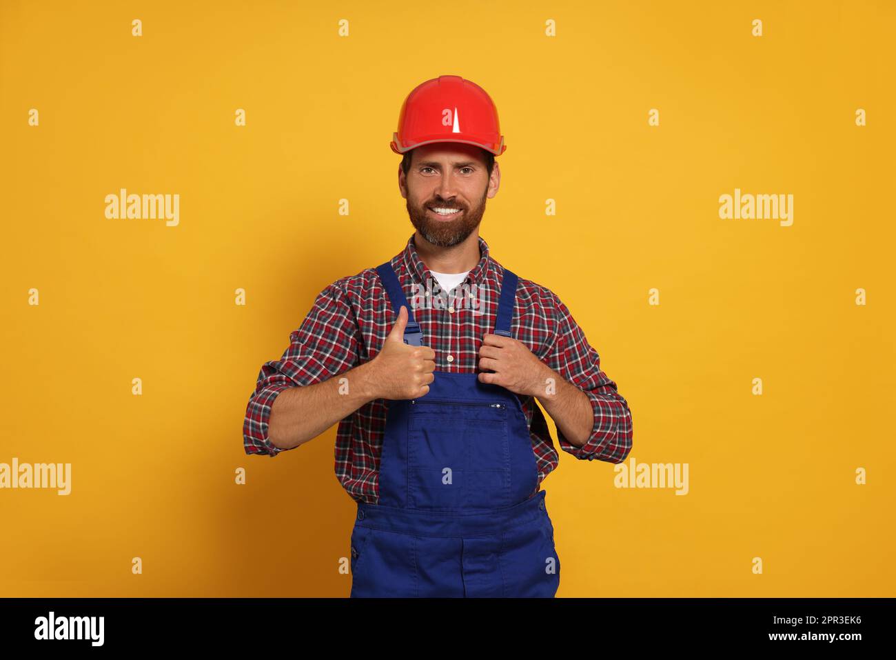 Professional builder in uniform on yellow background Stock Photo - Alamy