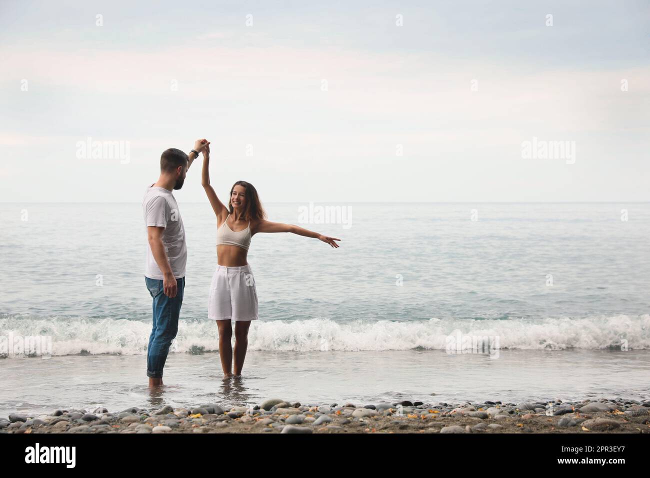 Happy young couple dancing on beach near sea. Space for text Stock ...