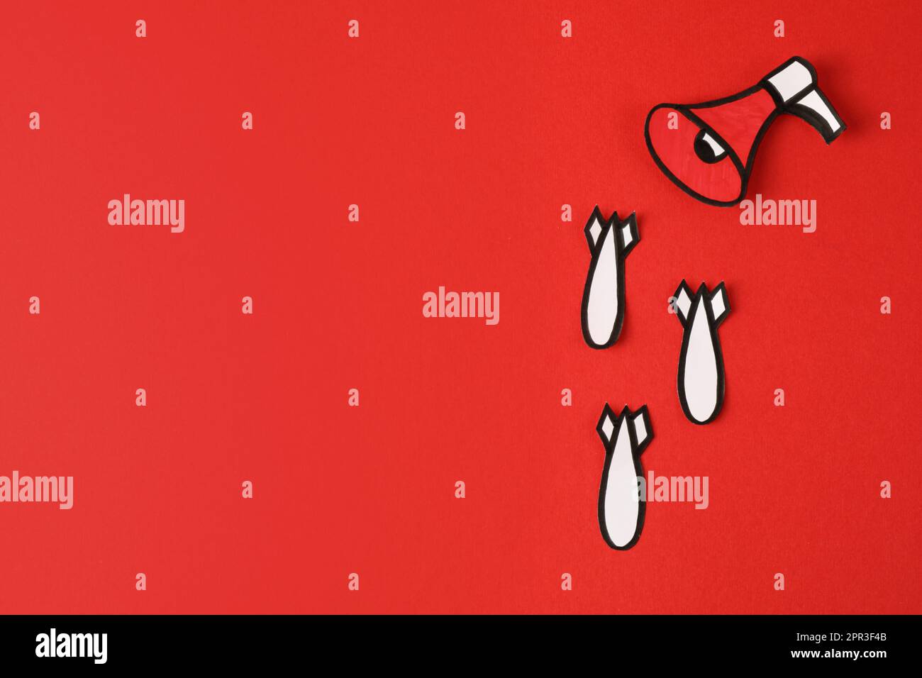 Paper megaphone and bombs on red background, flat lay with space for ...