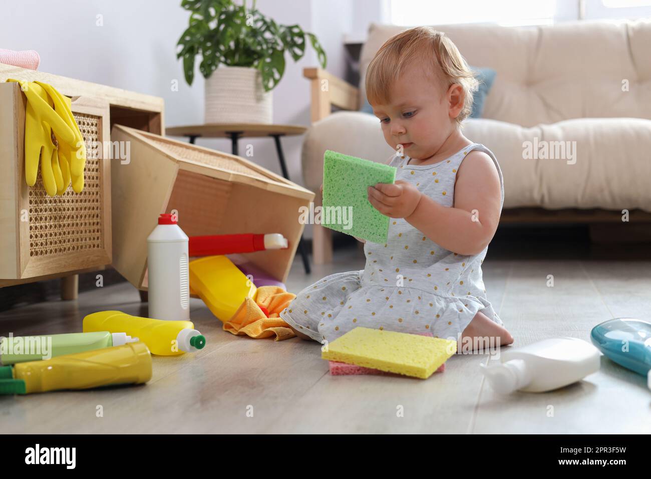 Cute baby playing with cleaning supplies on floor at home. Dangerous ...