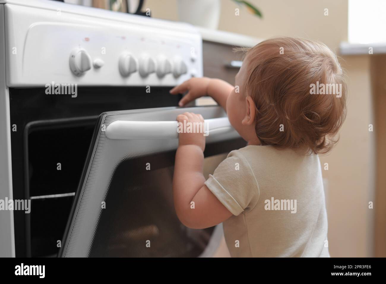 Little child opening oven indoors. Dangers in kitchen Stock Photo - Alamy
