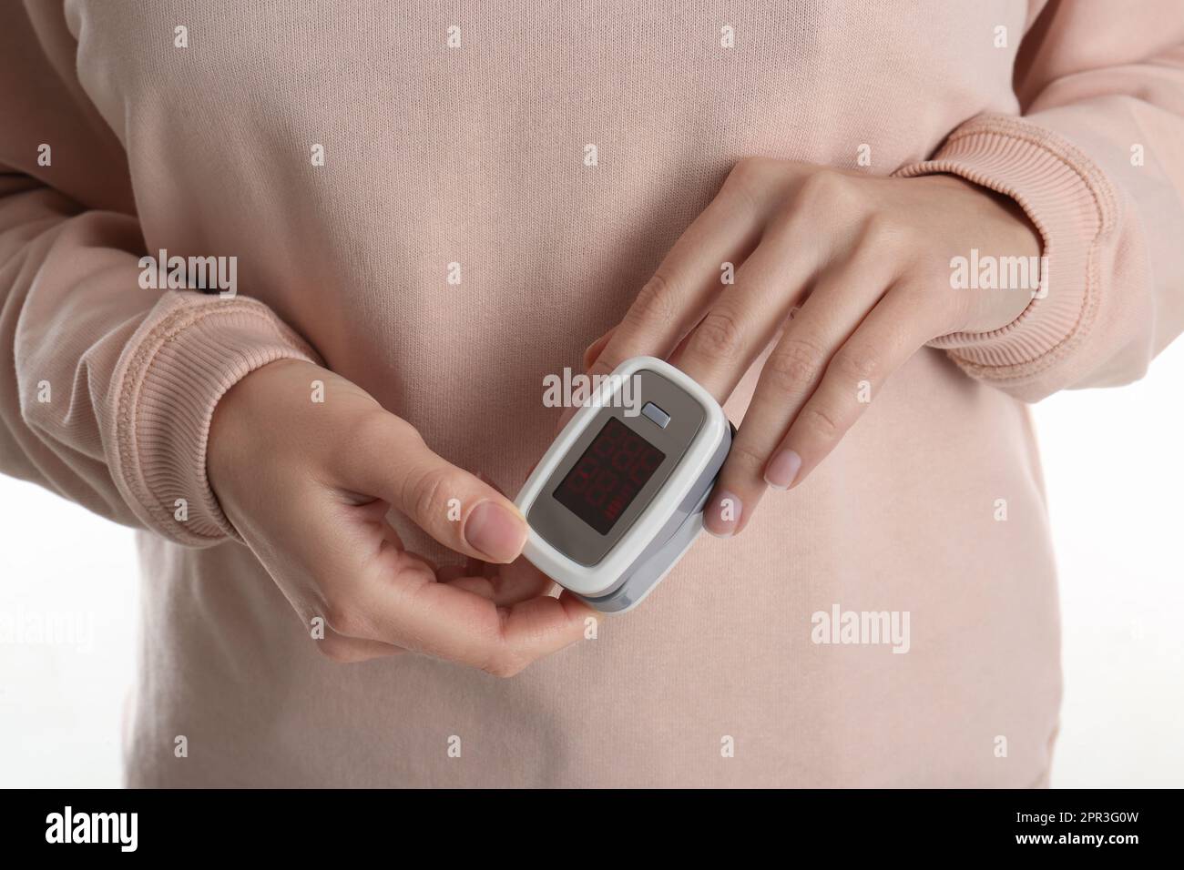 Woman using pulse oximeter for oxygen level testing on white background ...