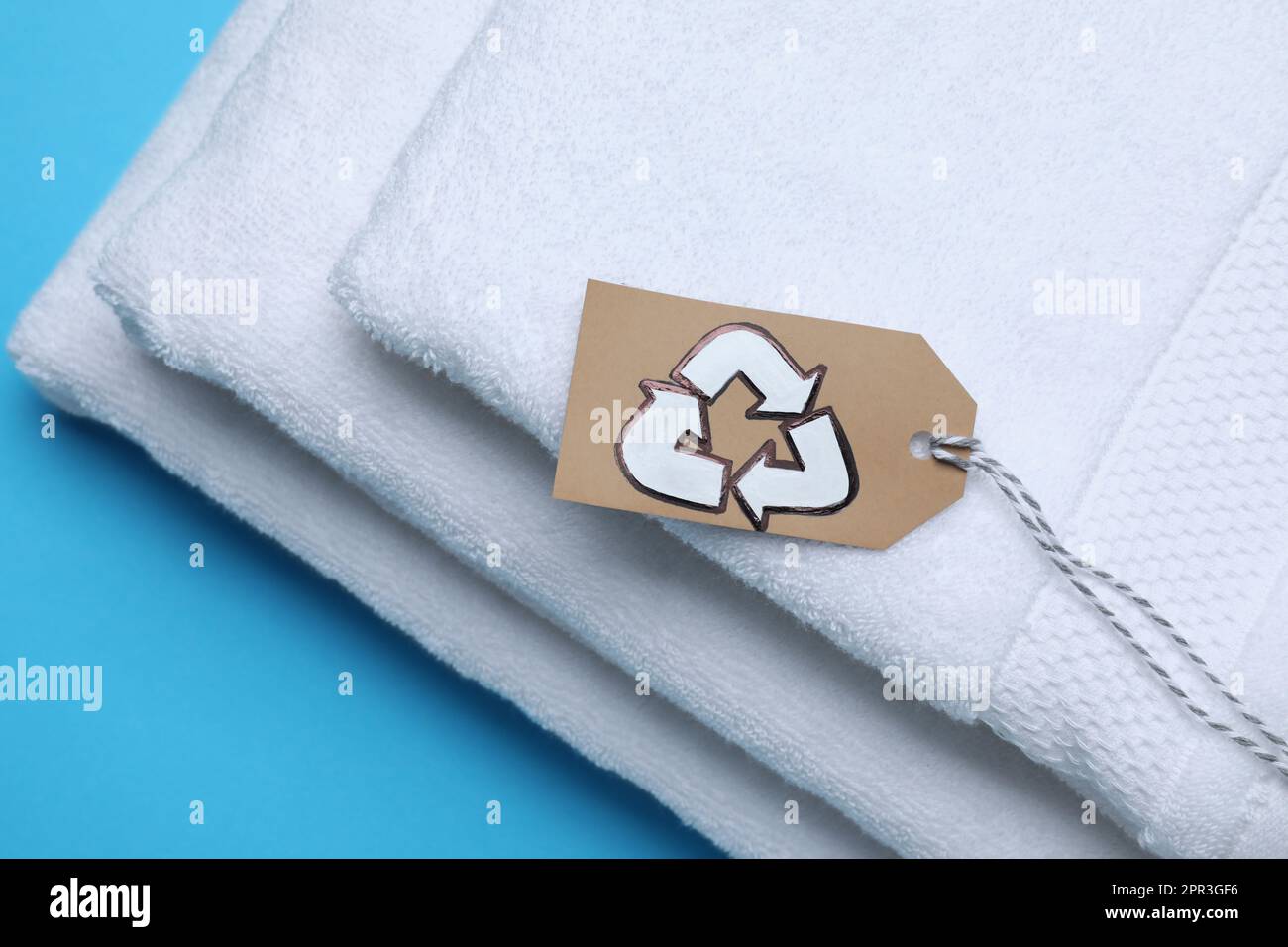 Stacked towels with recycling label on light blue background Stock ...