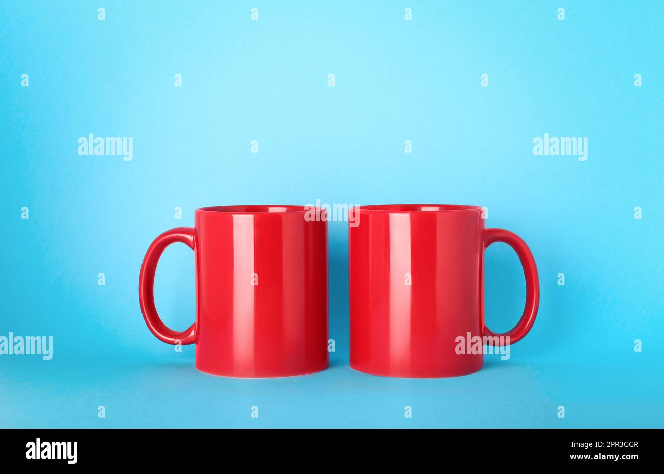 Blank red ceramic mugs on light blue background Stock Photo - Alamy