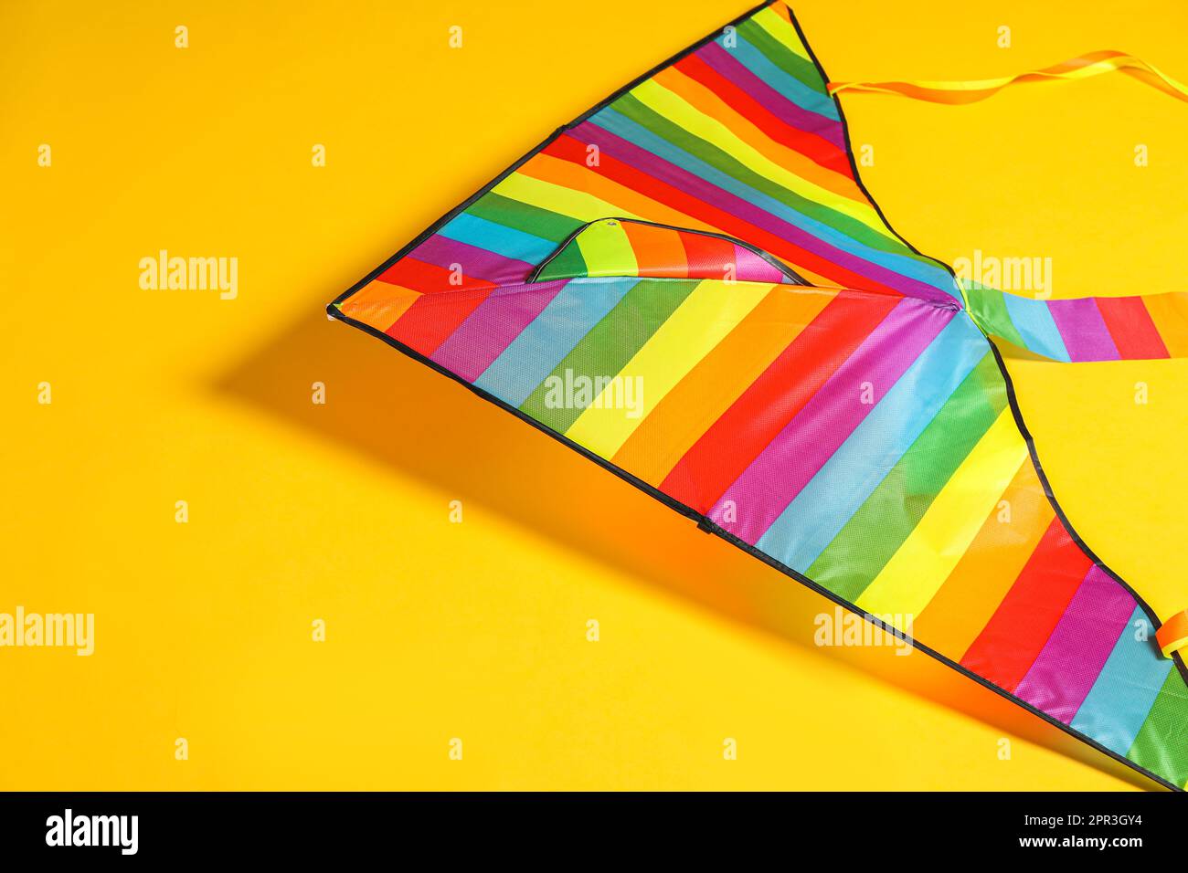 Beautiful bright rainbow kite on yellow background Stock Photo - Alamy