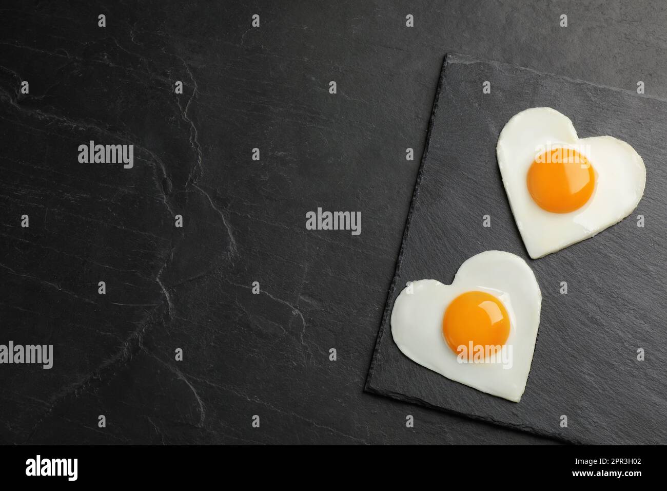 Heart shaped fried eggs on black table, top view. Space for text Stock Photo - Alamy