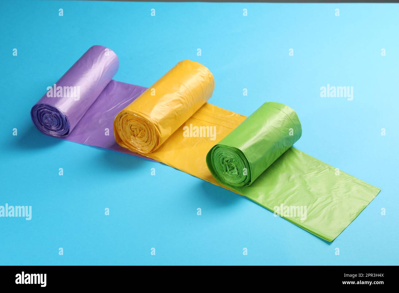Rolls of different garbage bags on light blue background Stock Photo ...