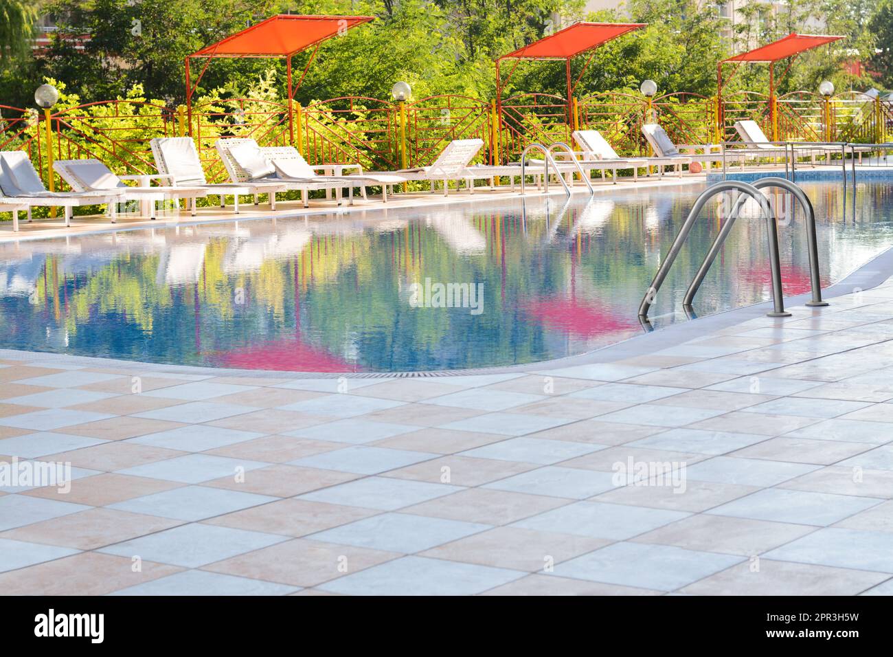 Outdoor swimming pool and many empty loungers at resort on sunny day ...