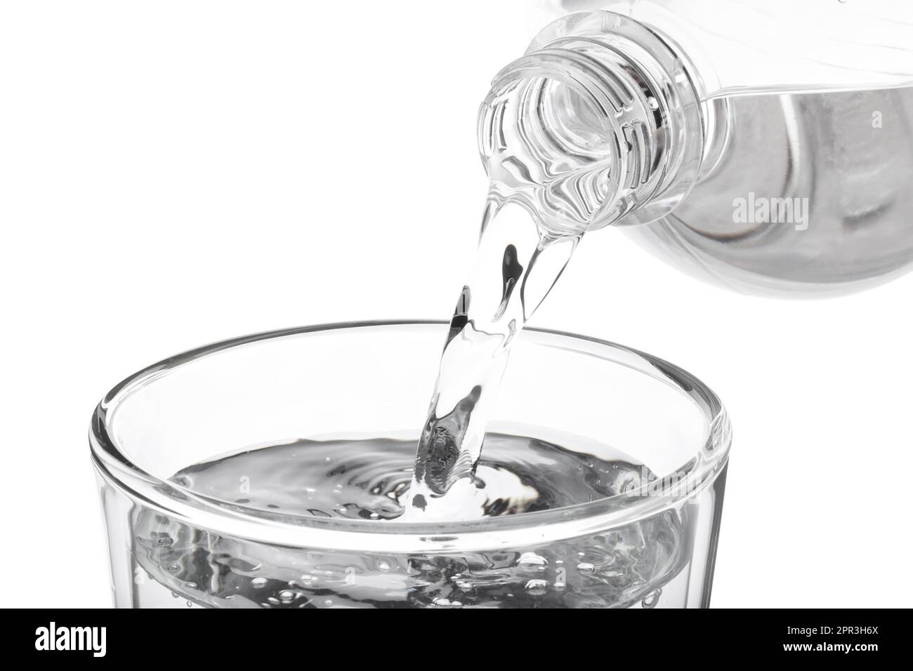 Pouring soda water from bottle into glass on white background, closeup ...
