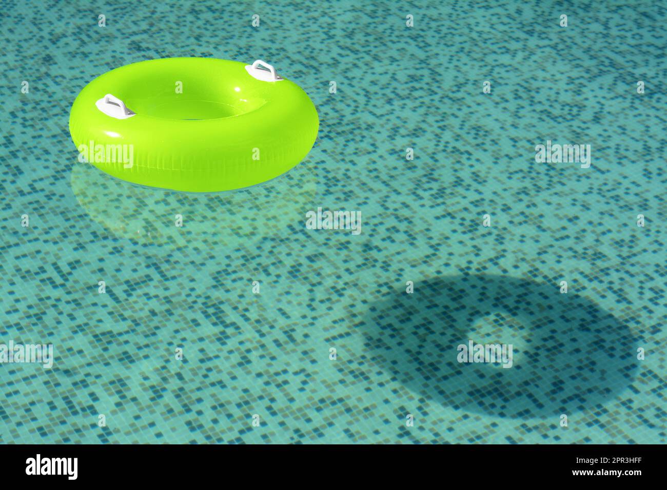 Light green inflatable ring floating in swimming pool. space for text ...