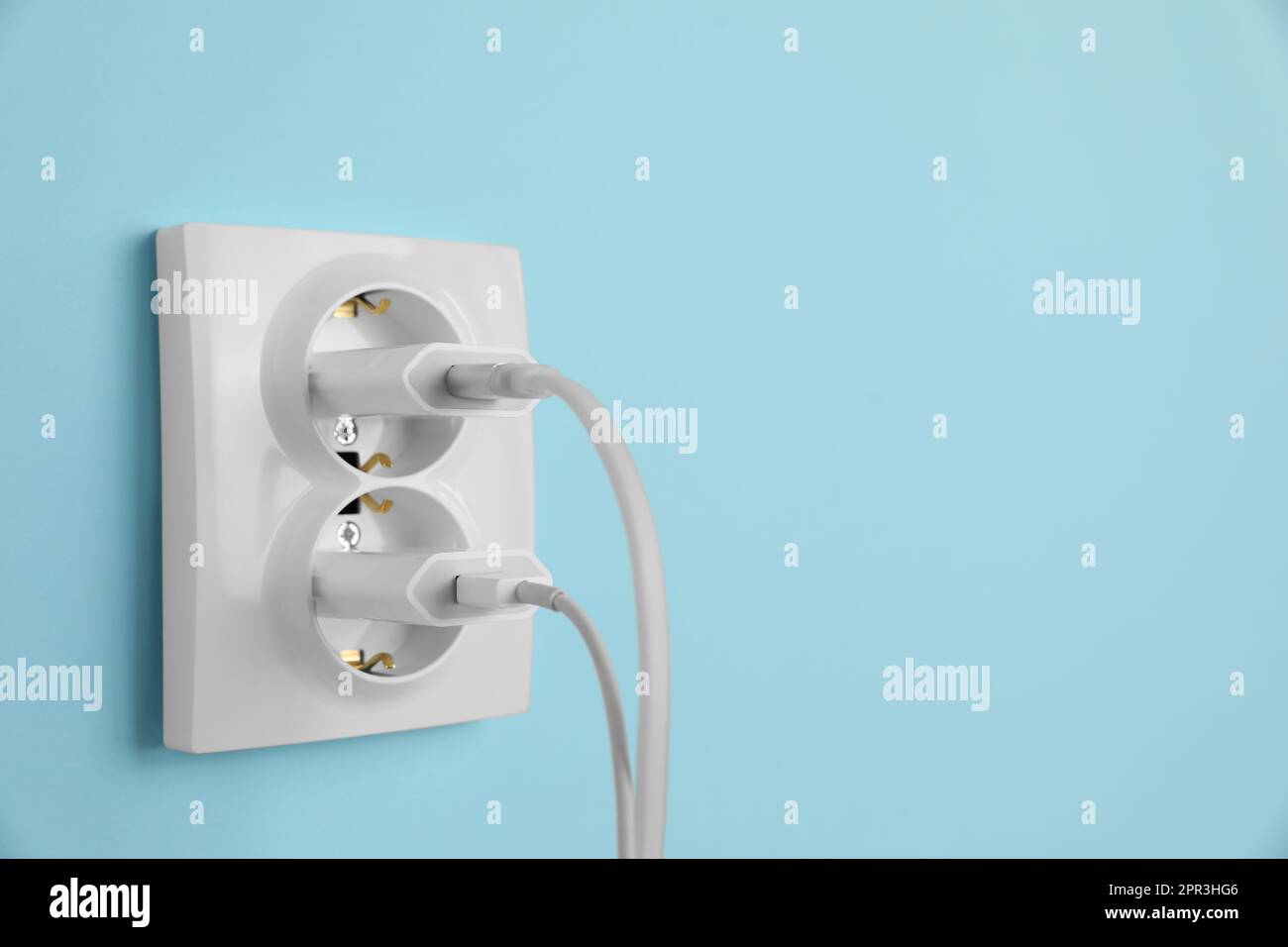 Charger adapters plugged into power sockets on light blue wall, space ...