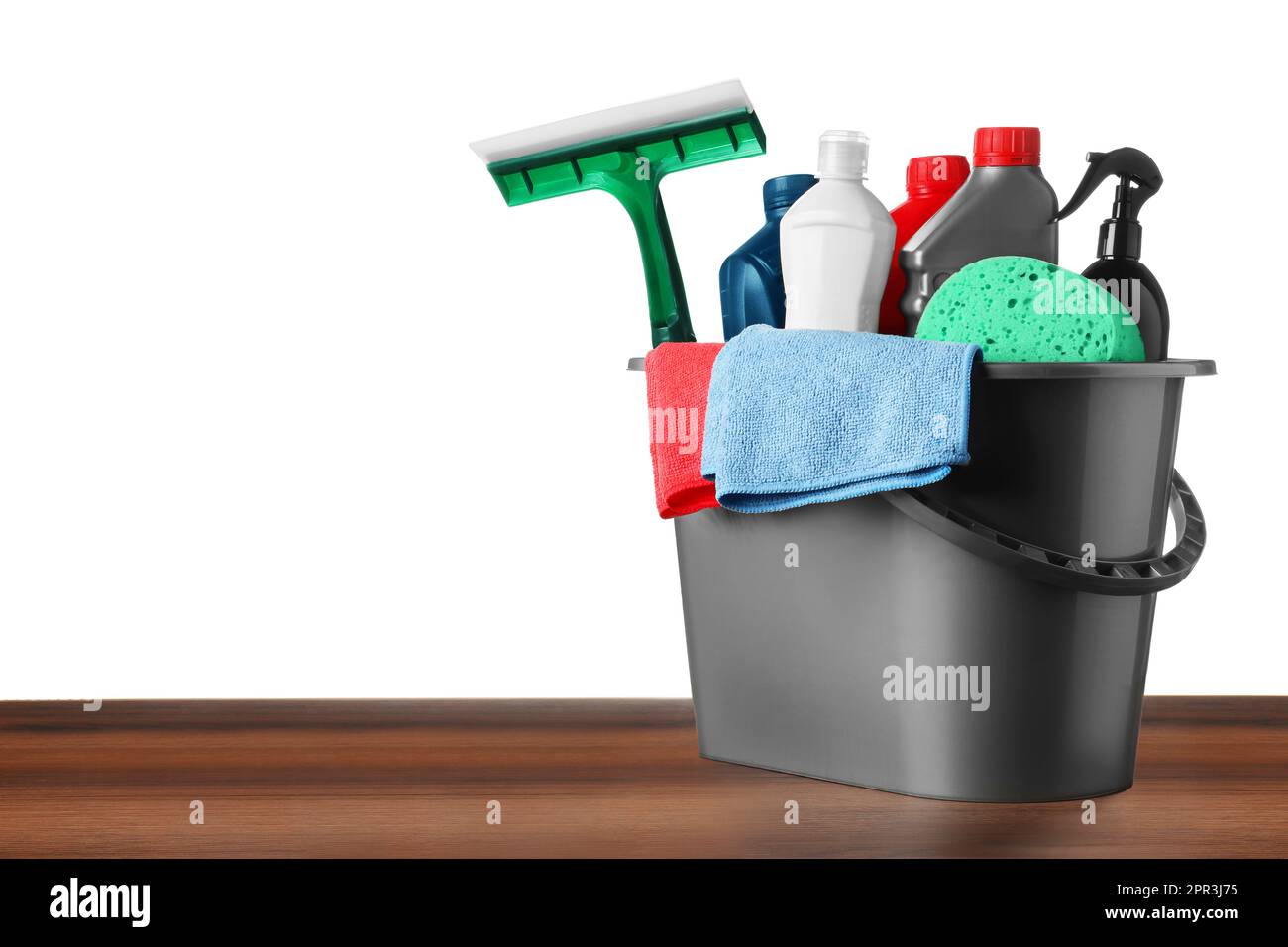 Grey bucket with car care products on wooden table against white ...